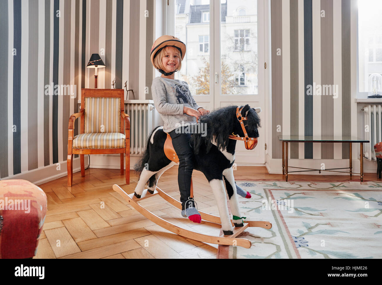 Happy girl posing on rocking horse Stock Photo - Alamy
