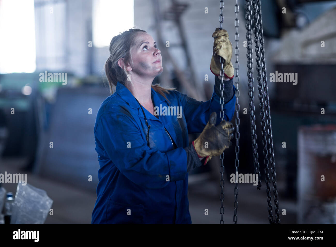 Woman pulling a chain in workshop Stock Photo - Alamy