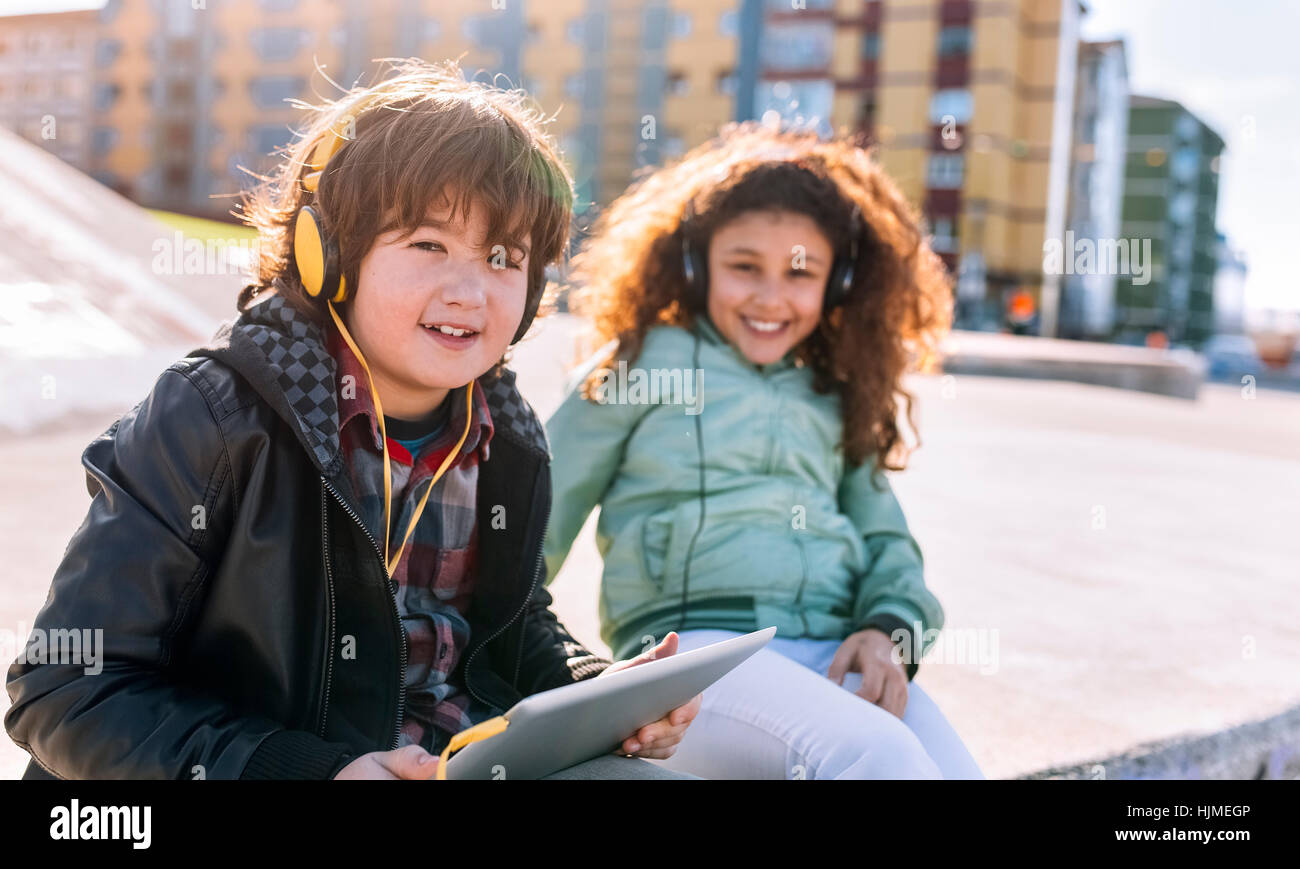 Two children listening music with headphones and tablet Stock Photo - Alamy