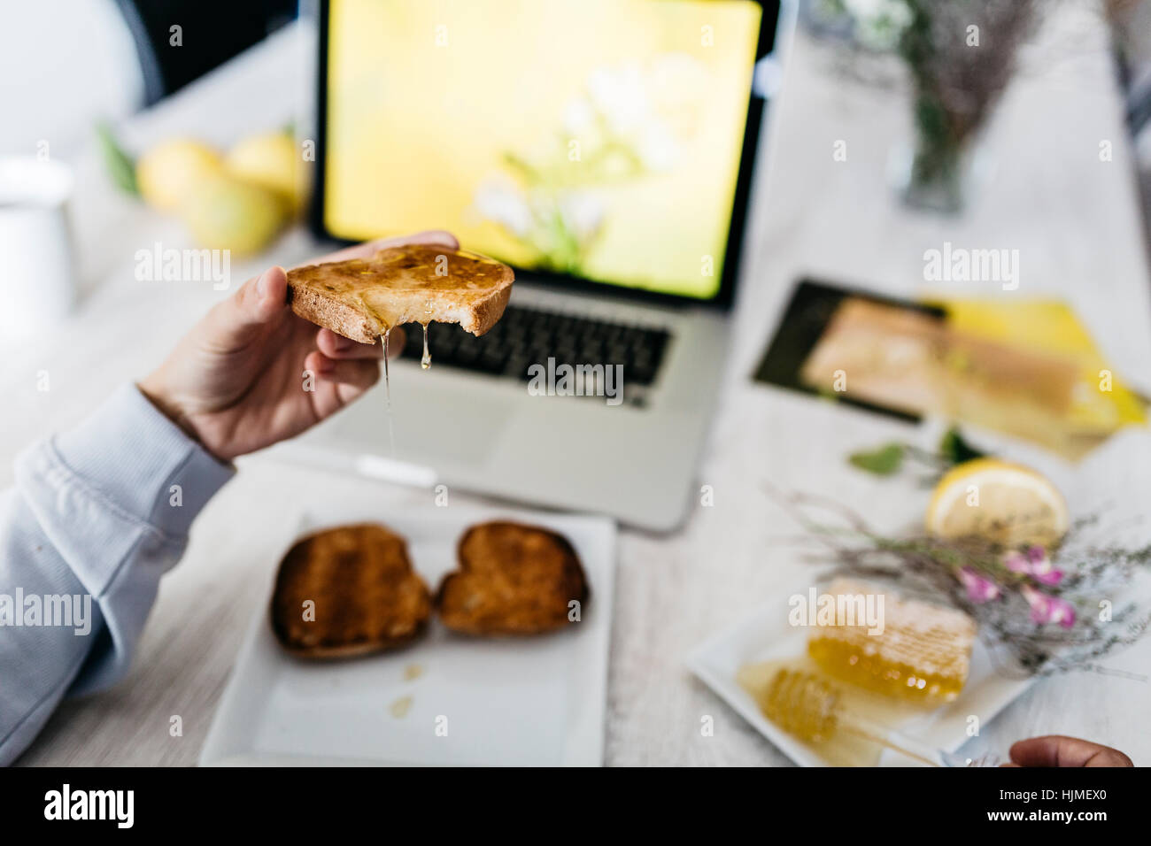 Man's hand holding bitten toast with dripping honey at his workplace ...