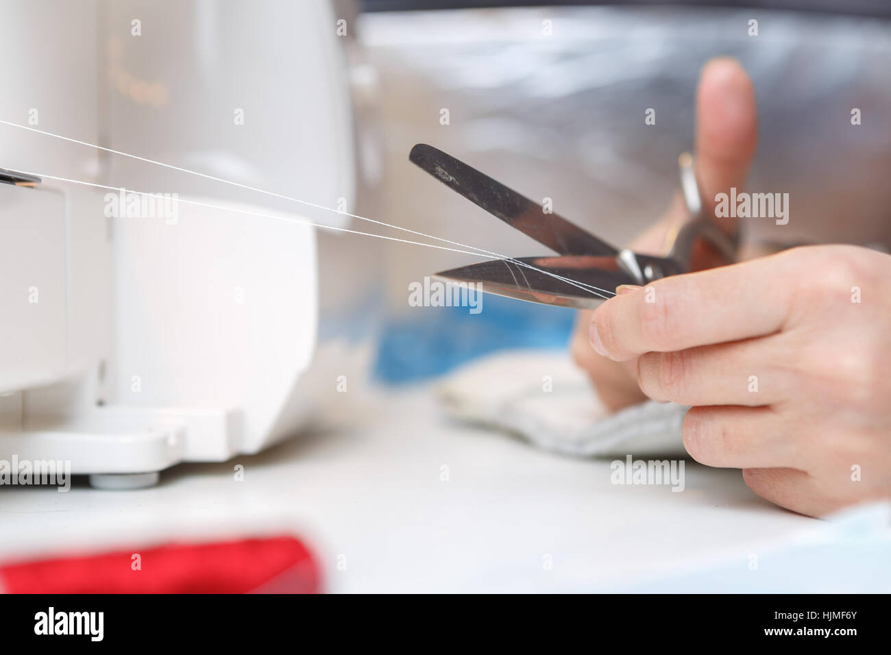 Girl with scissors cuts thread Stock Photo - Alamy