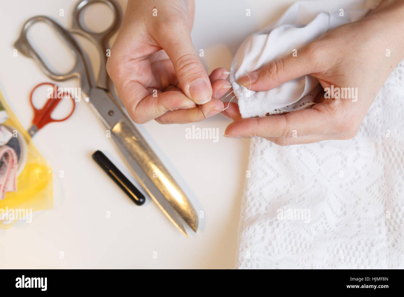 Girl unpick fabric on table Stock Photo - Alamy