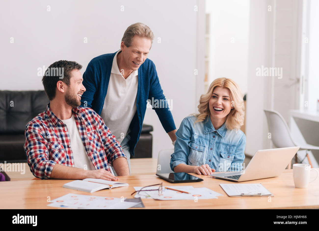Handsome nice man standing behind his colleagues Stock Photo - Alamy