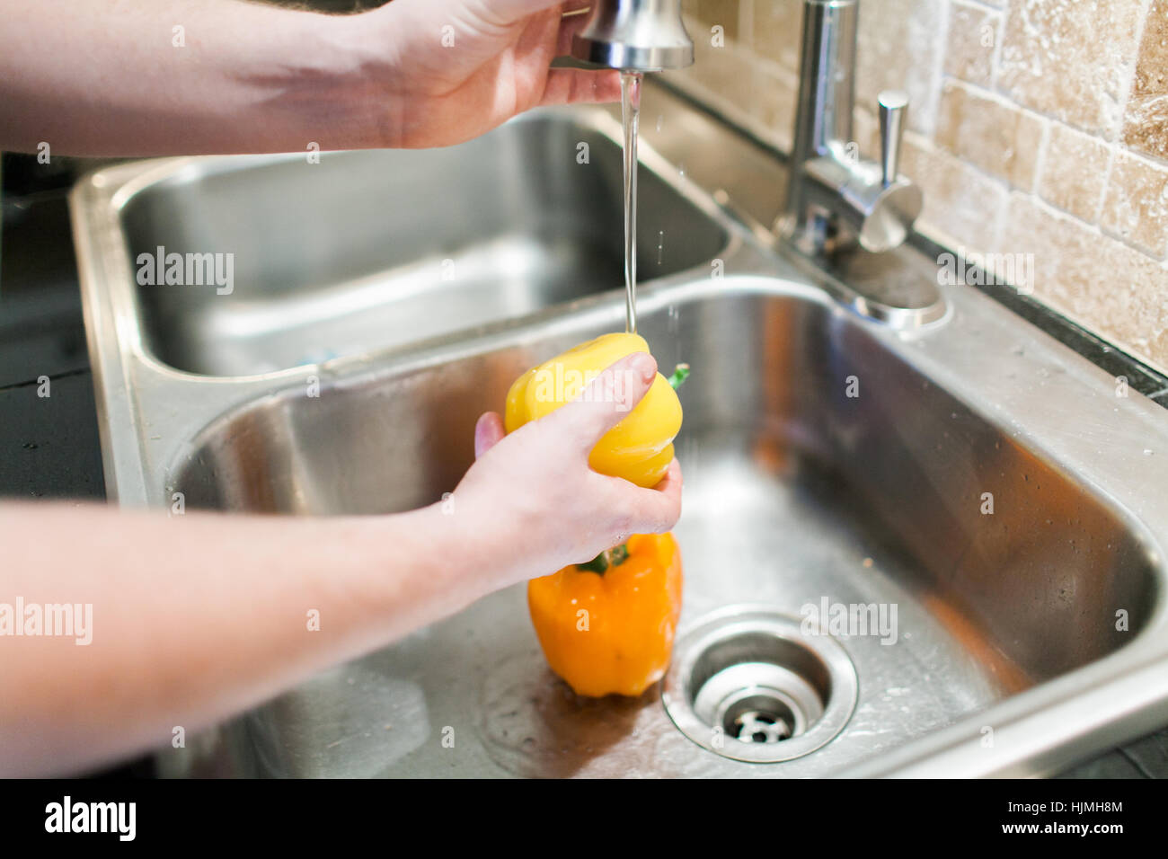 Washing a yellow bell pepper in a sink Stock Photo - Alamy