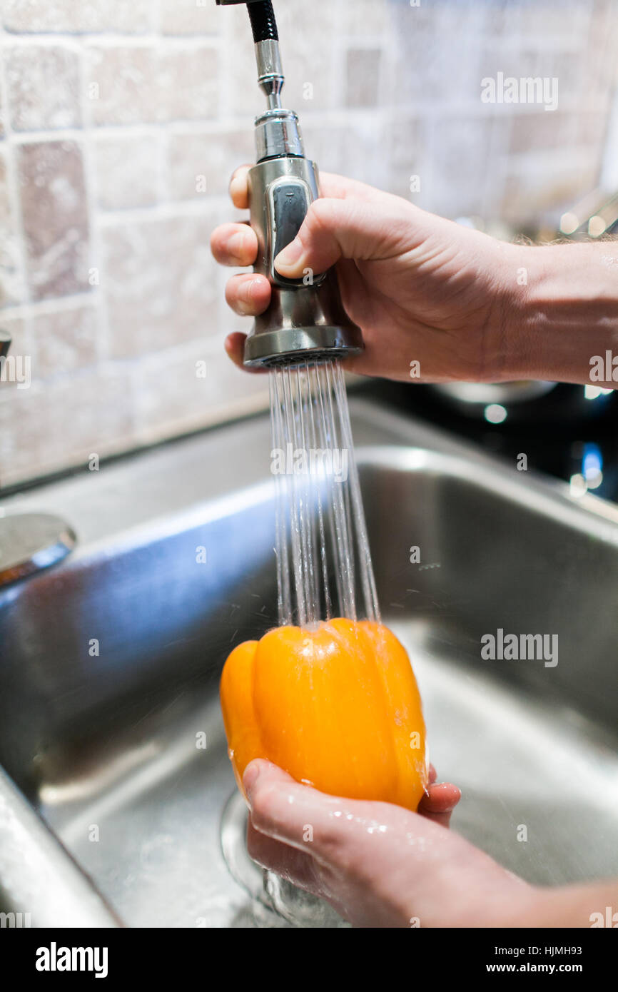 Man washing a yellow bell pepper in a sink Stock Photo - Alamy
