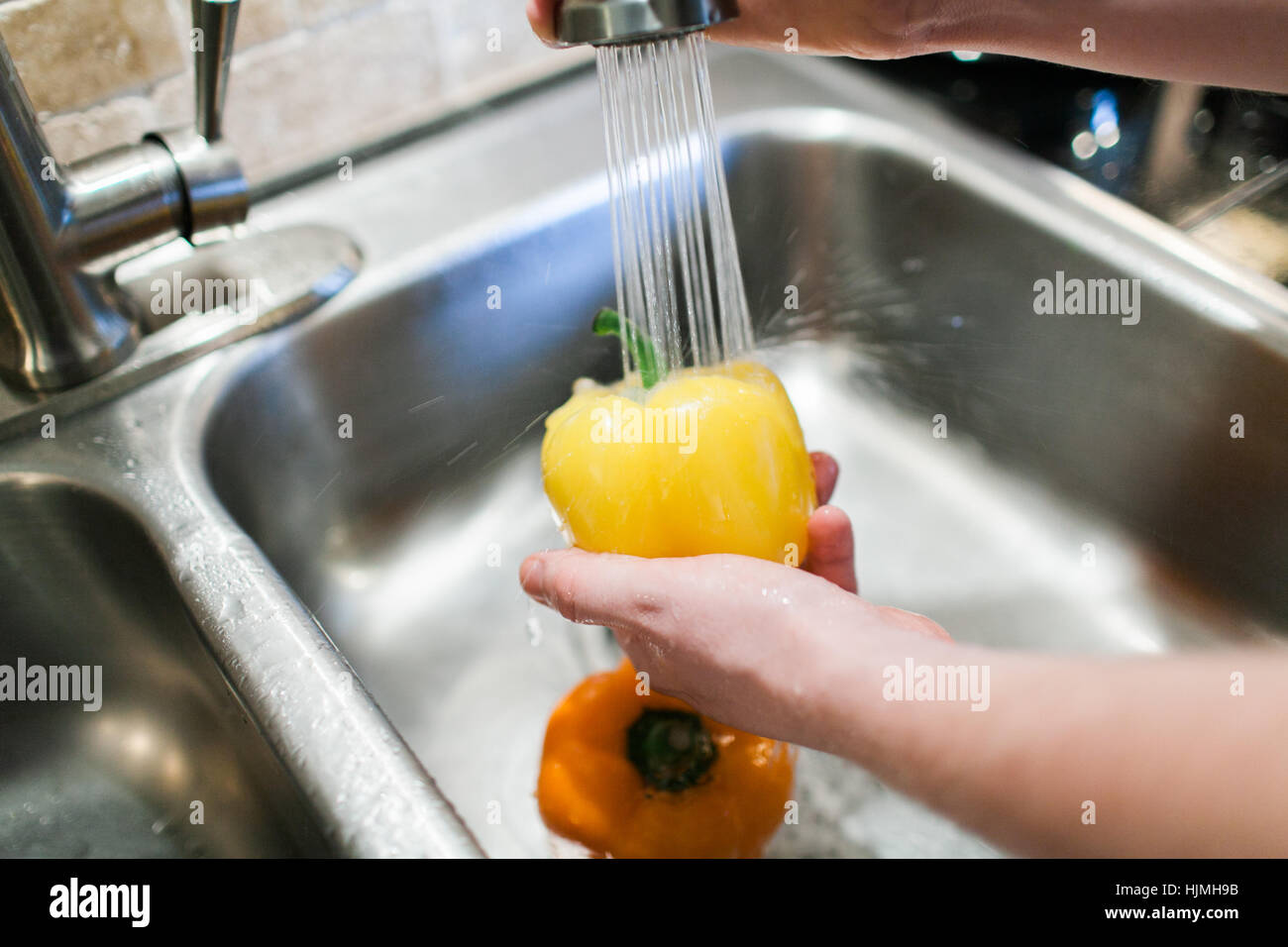 Man washing a yellow bell pepper in the sink Stock Photo - Alamy
