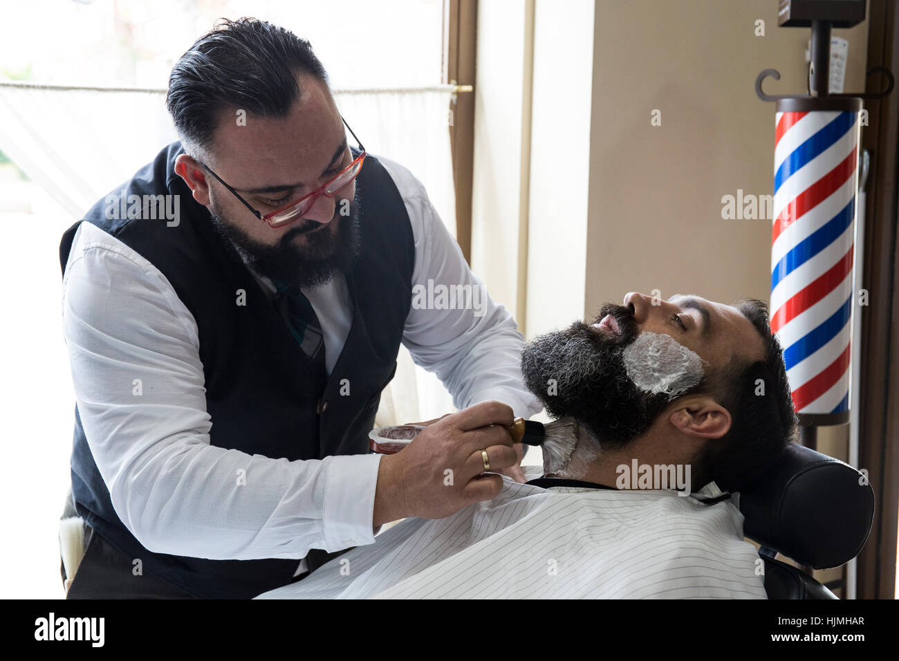 Barber putting shaving foam in man's beard Stock Photo - Alamy