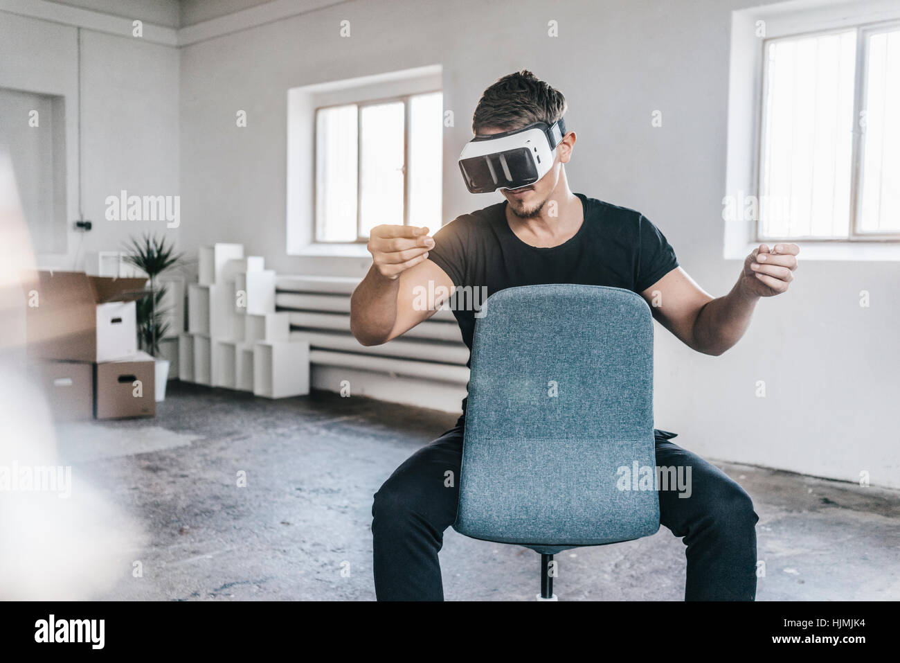 Man sitting on chair in empty loft wearing VR glasses Stock Photo - Alamy