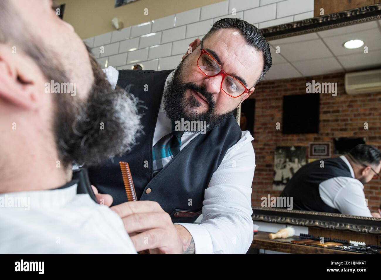 Barber cutting man's beard Stock Photo - Alamy