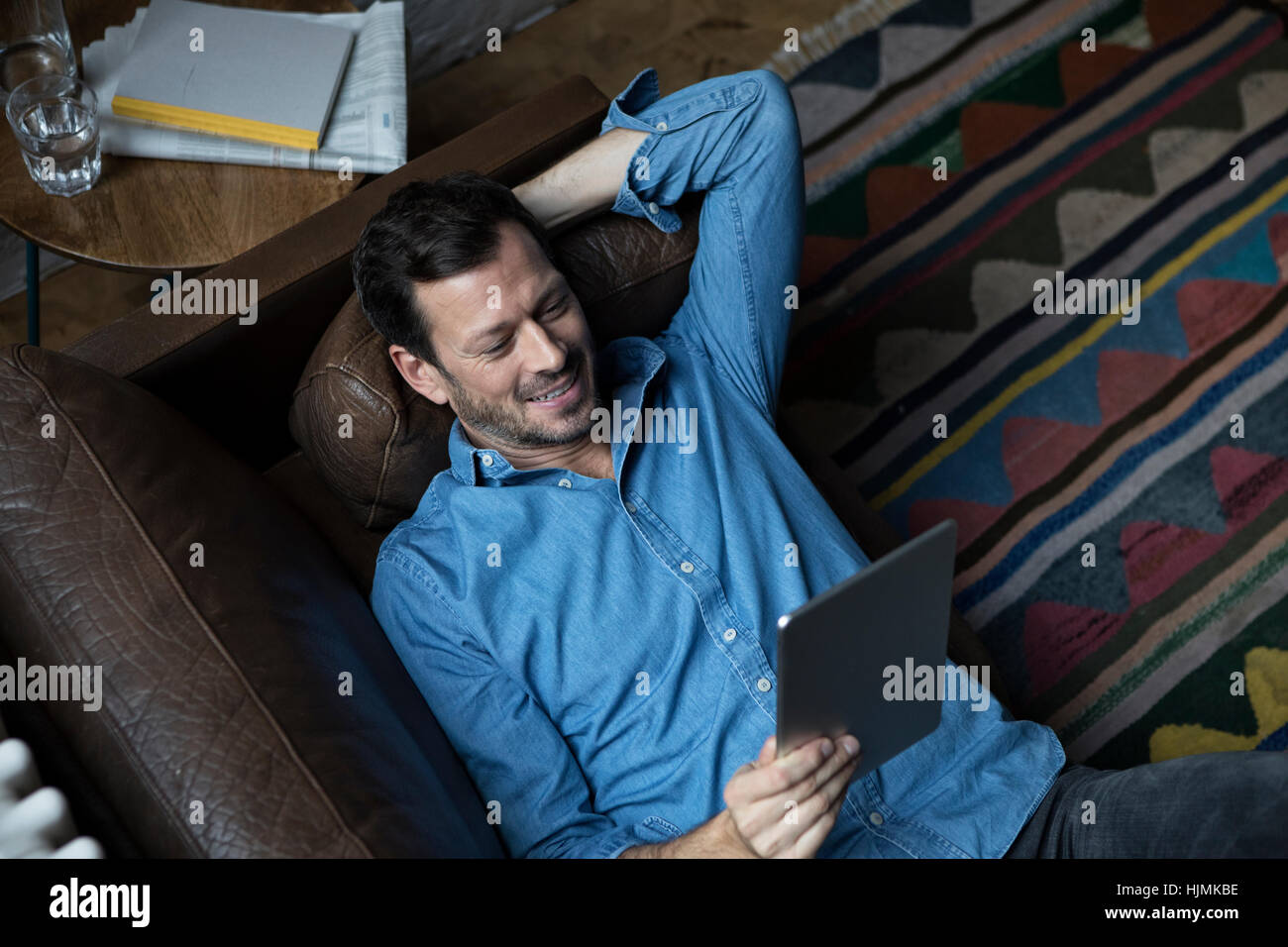 Man lying on couch, using digital tablet Stock Photo - Alamy