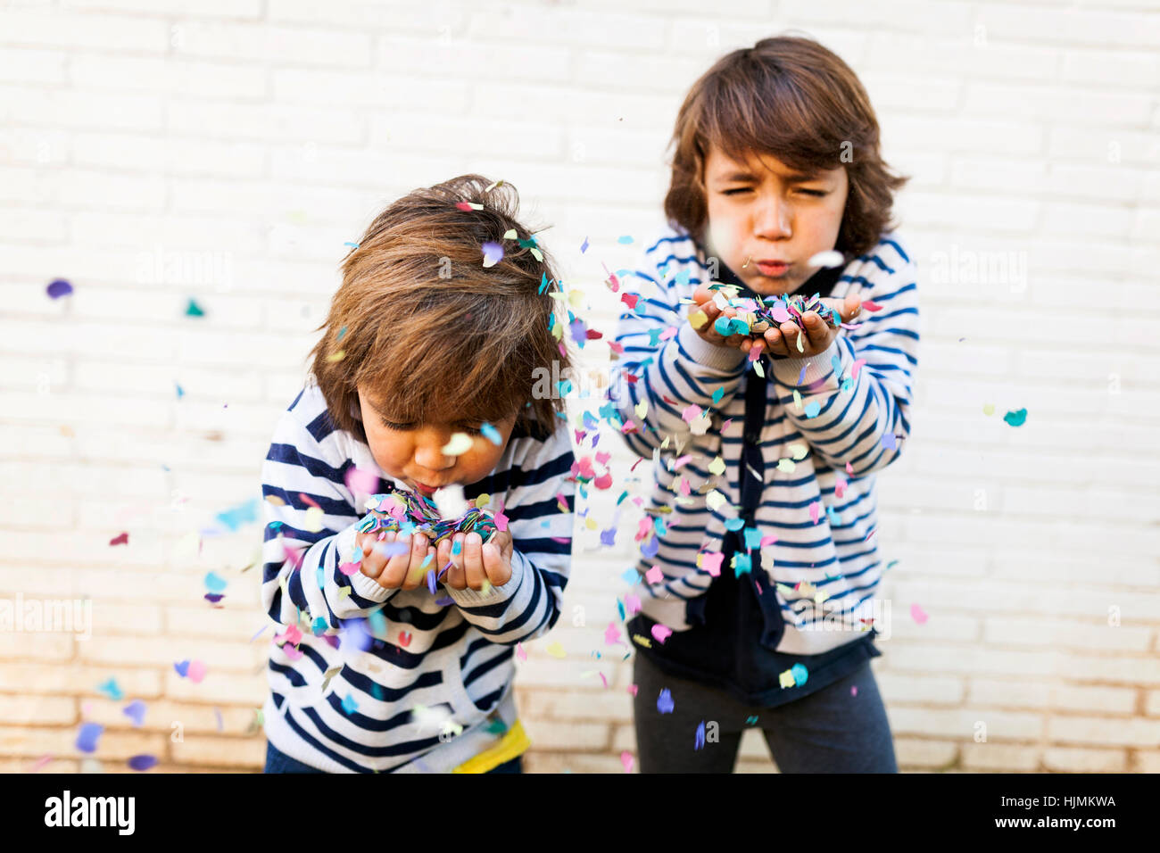 Boys blowing colorful confetti from there hands Stock Photo - Alamy