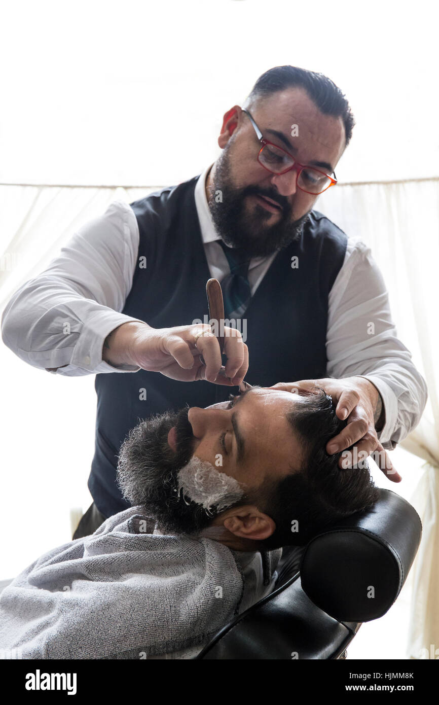 Barber shaving a man using a straight razor Stock Photo - Alamy