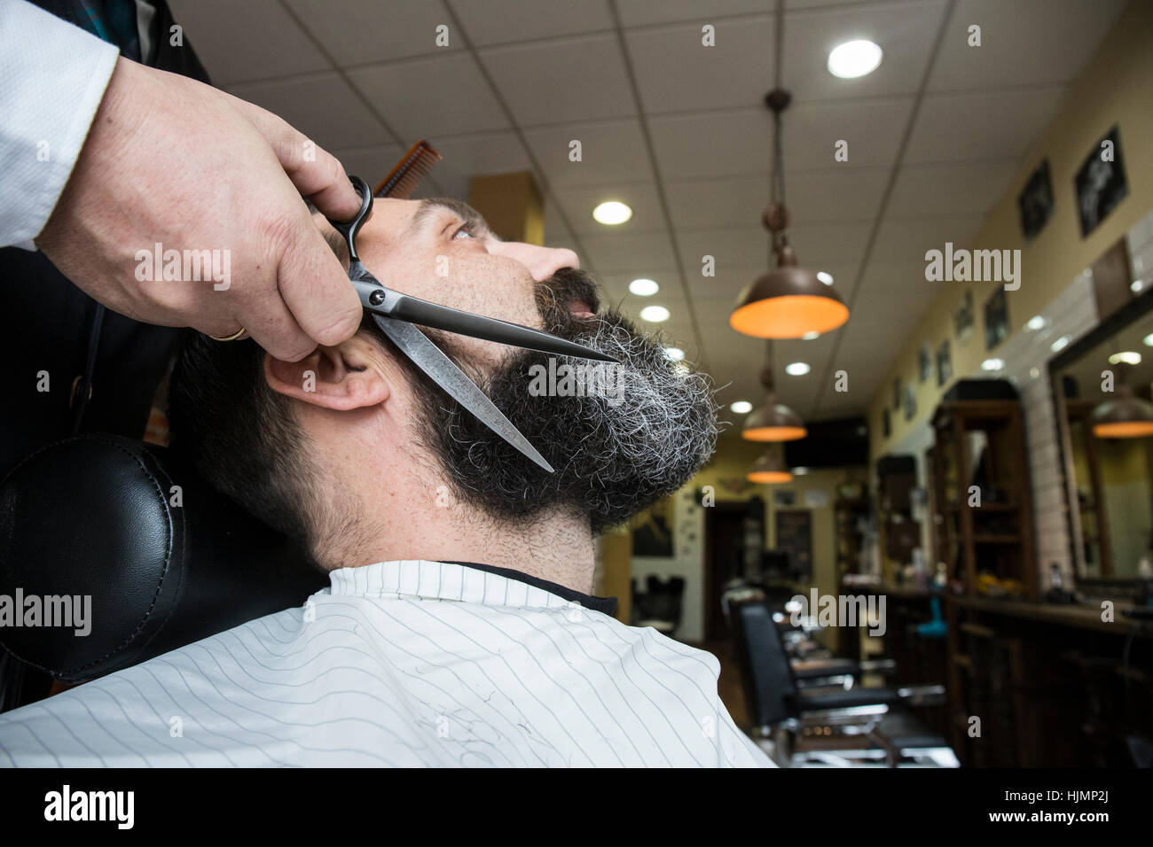 Barber cutting man's beard Stock Photo - Alamy