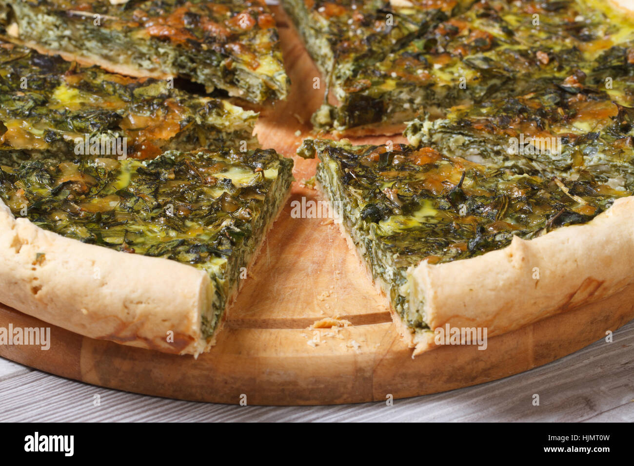 sliced pie with spinach and soft cheese closeup on chopping board ...