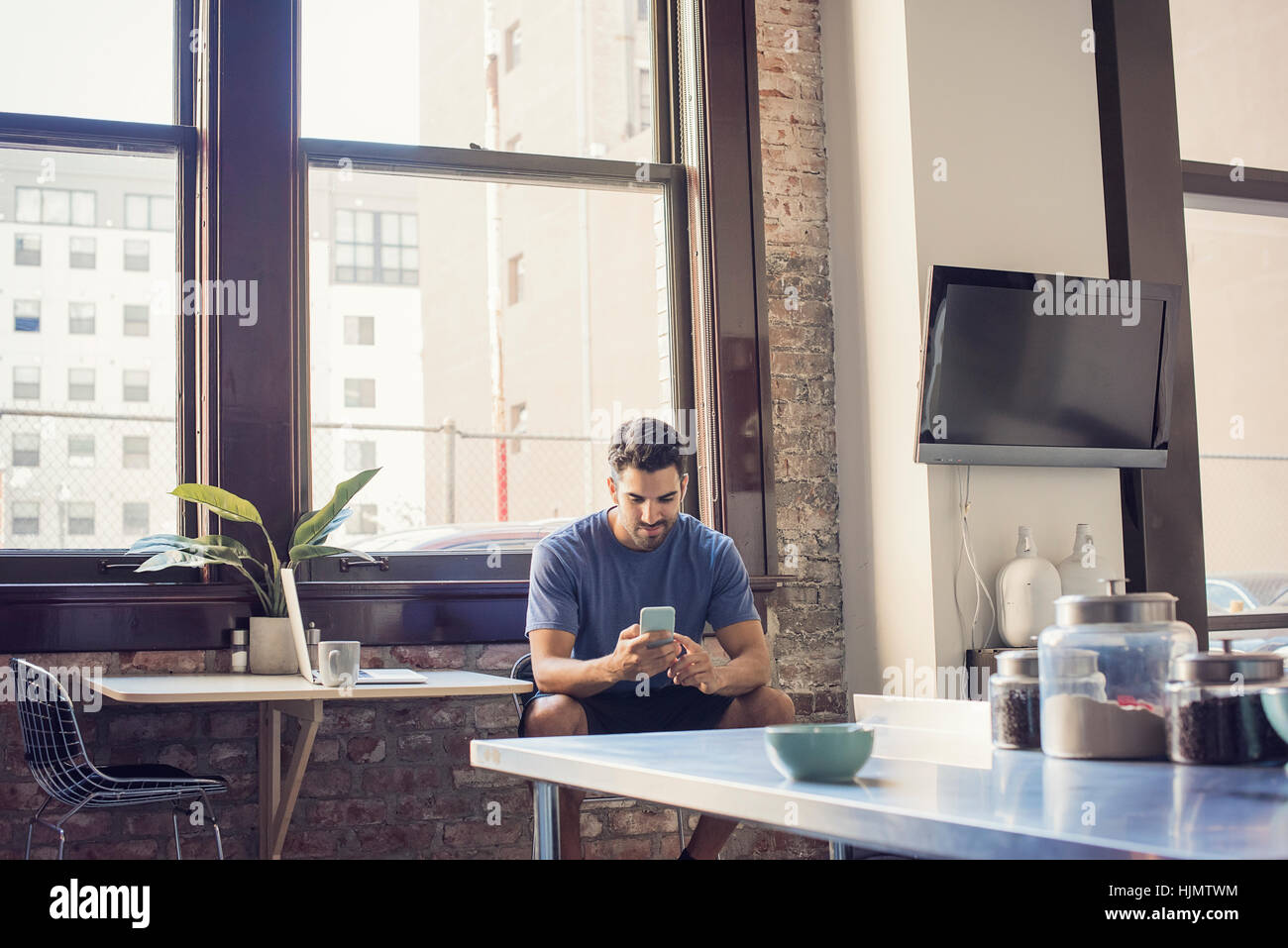 Young man standing in kitchen using smart phone Stock Photo - Alamy