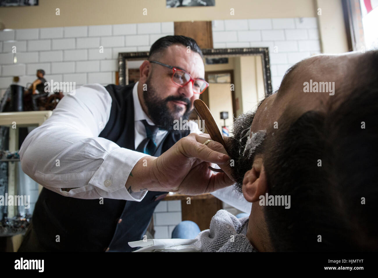 Barber shaving a man using a straight razor Stock Photo - Alamy