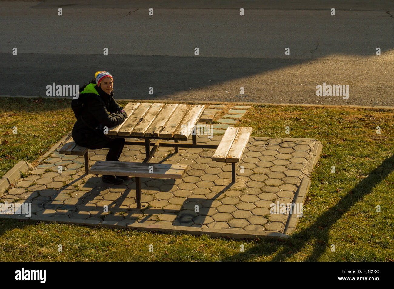 Young woman in the distance sitting alone on a bench Stock Photo - Alamy