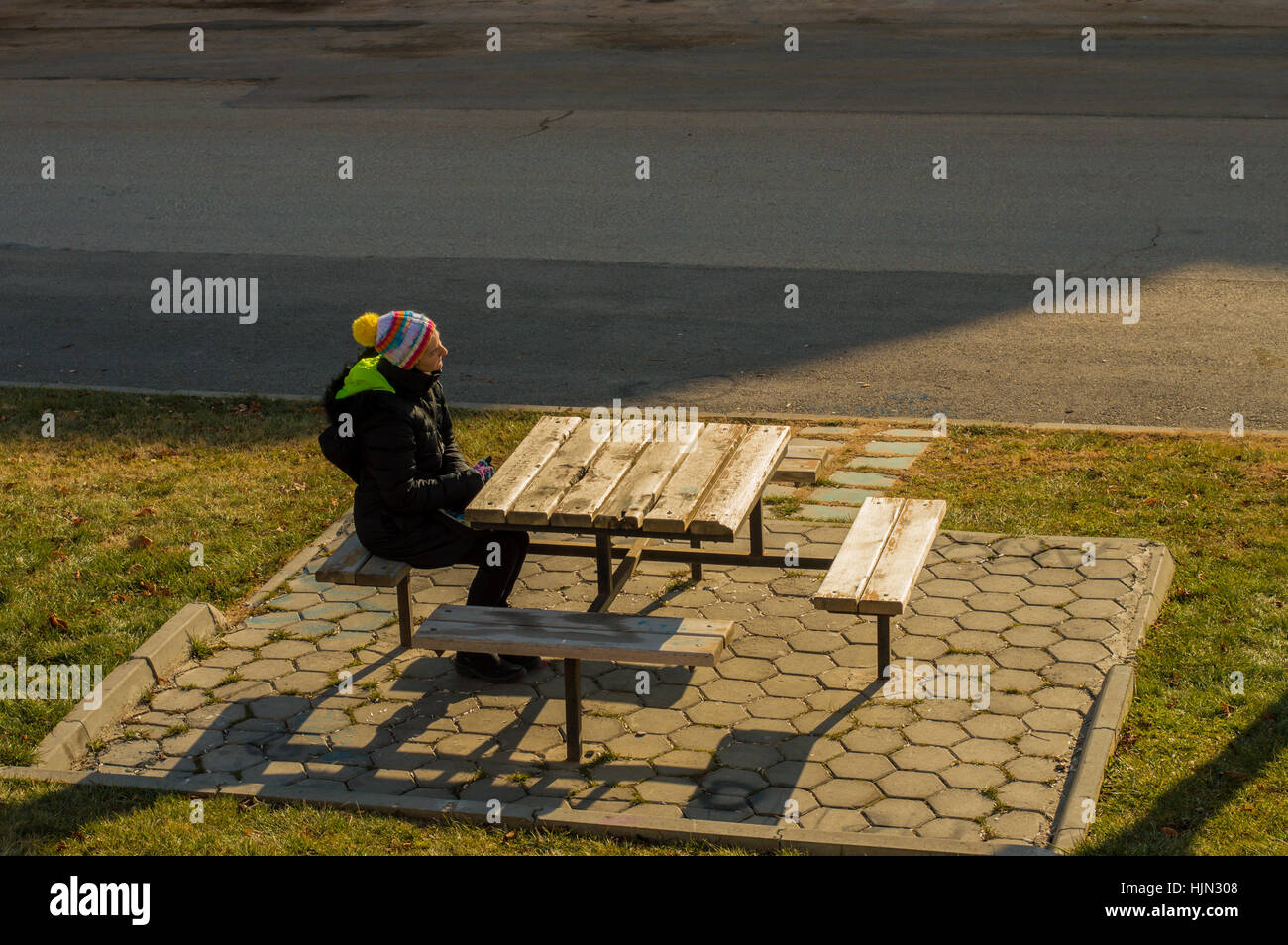 Young woman in the distance sitting alone on a bench Stock Photo - Alamy