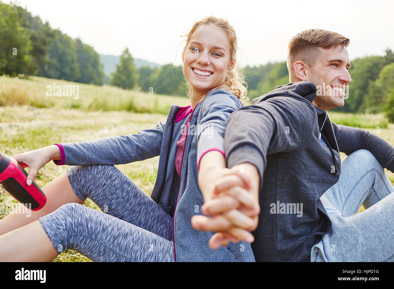 Exhausted couple taking a break happily holding hands in the nature ...