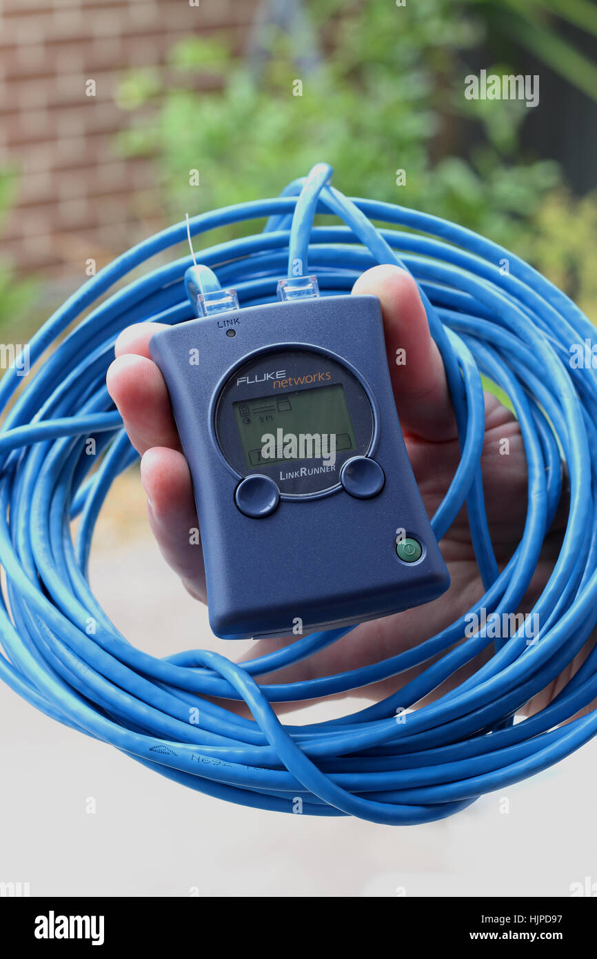 Hand holding Fluke Networks LinkRunner device with blue cabling Stock ...