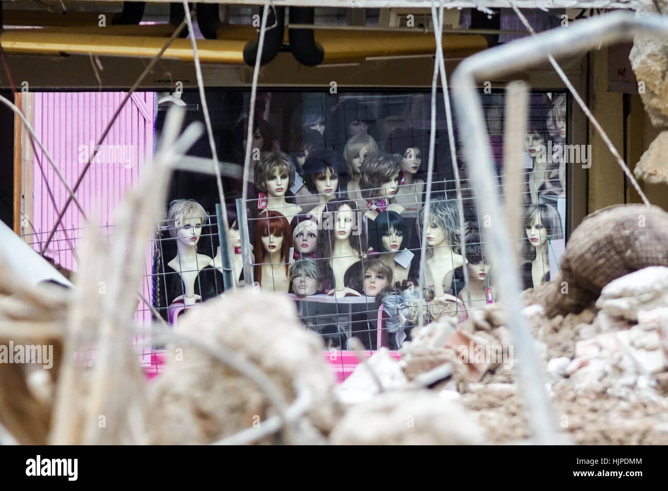 mannequin heads in window seen through a pile of rubble on a building ...