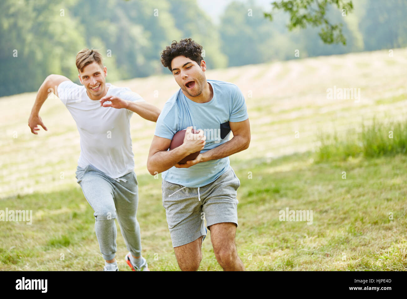 Men playing rugby in the park as friends having fun Stock Photo - Alamy