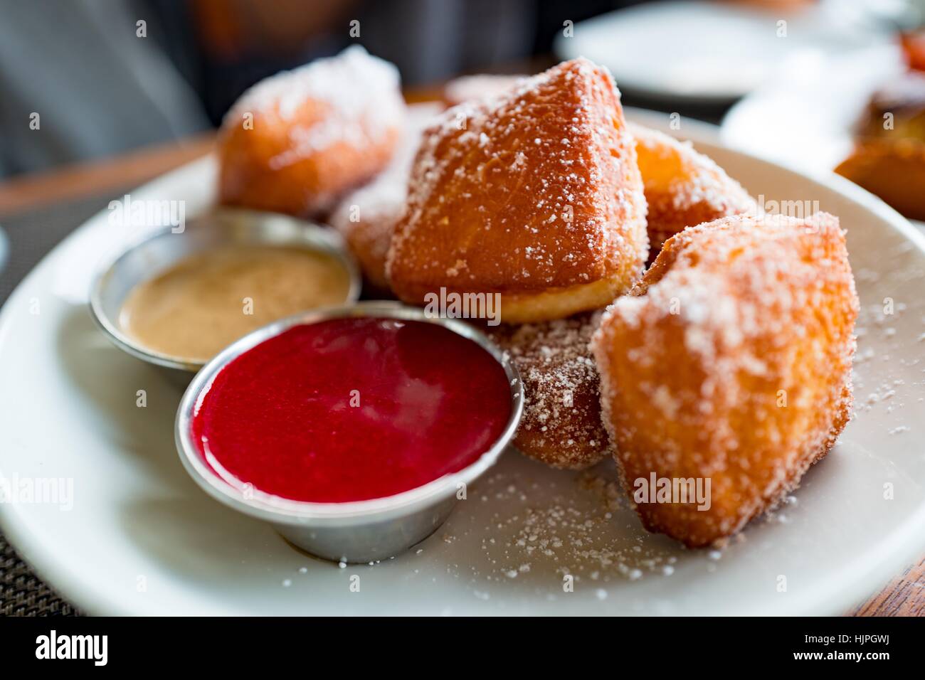 Close up of beignet donuts with raspberry dipping sauce on a white ...