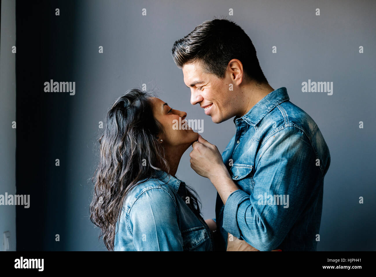 Happy couple smiling and kissing at home Stock Photo - Alamy