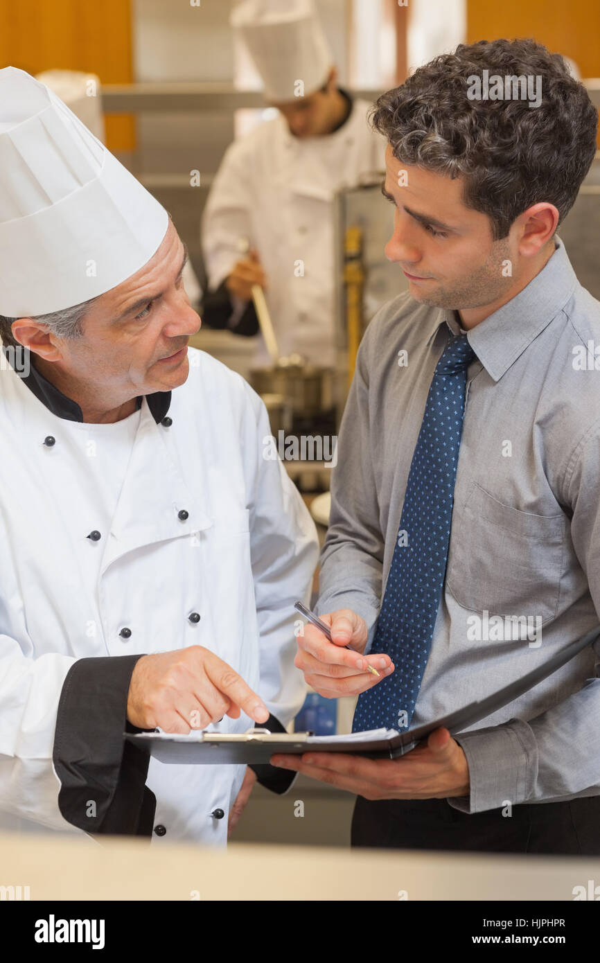 Chef and waiter having a discussion in the kitchen Stock Photo - Alamy