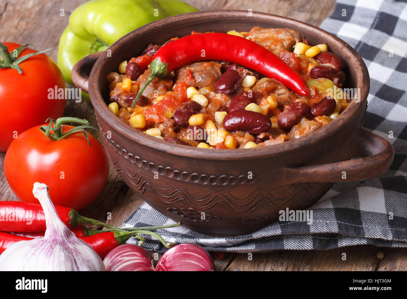 hot chili con carne in a saucepan and ingredients on the table ...