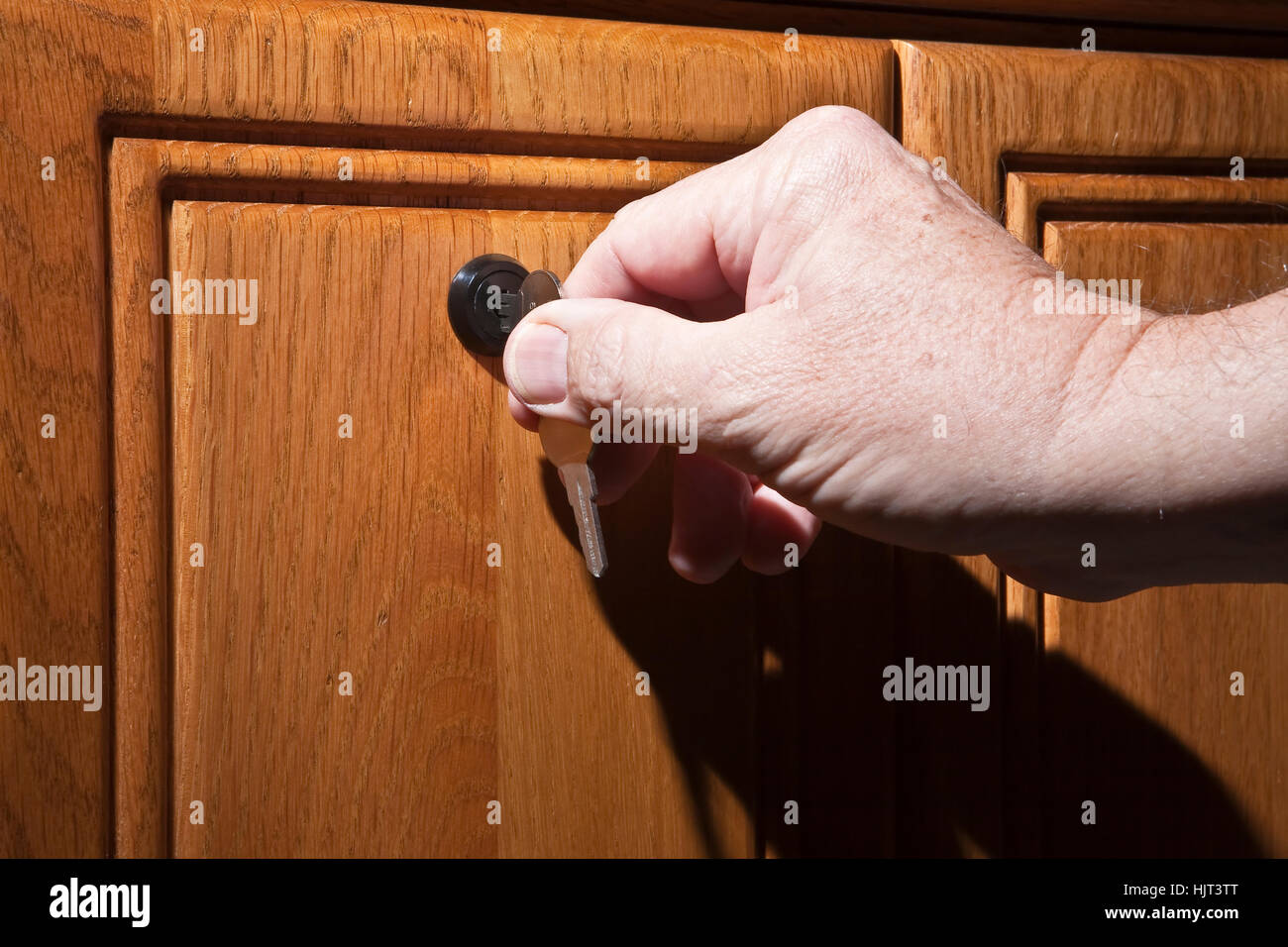 Older man's hand turning key in lock of wooden desk Stock Photo - Alamy