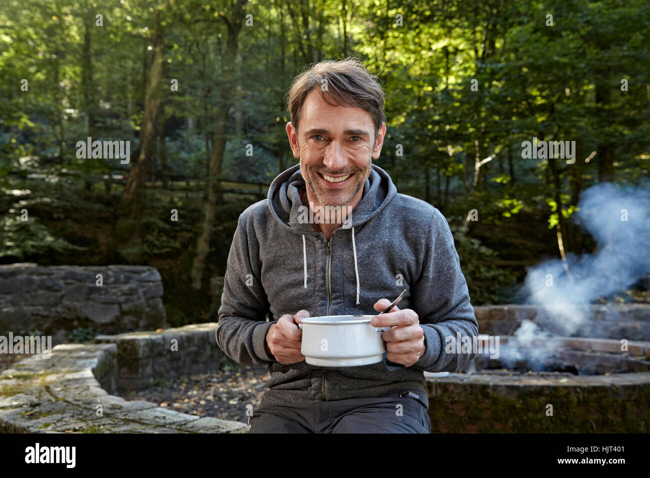 Portrait of man holding pot at camp fire Stock Photo - Alamy