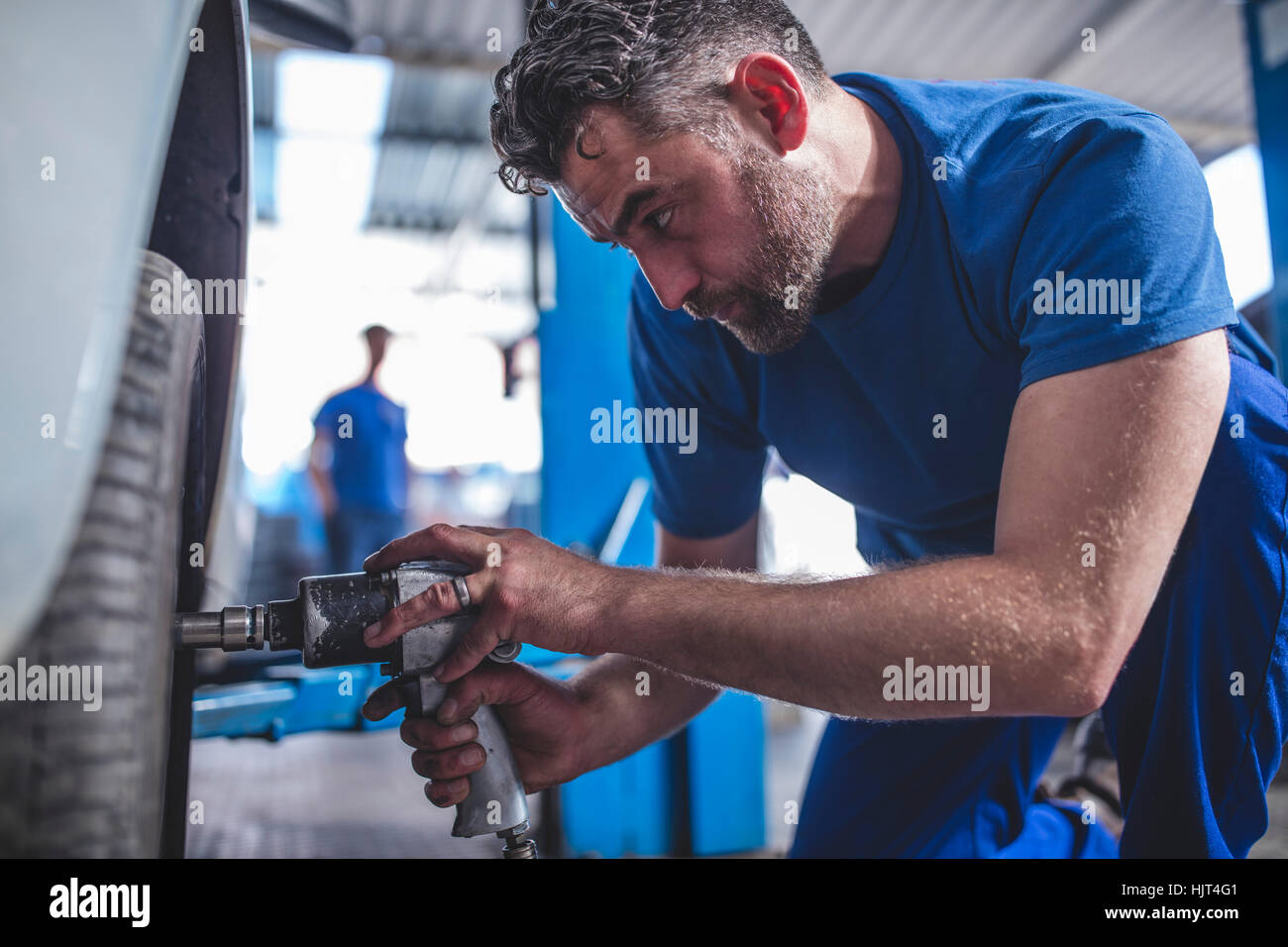 Car mechanic in a workshop changing tyre Stock Photo - Alamy