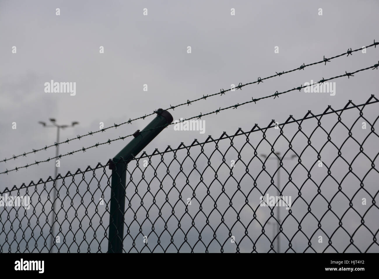 Barbed wire fence and wire mesh fence in front of grey sky Stock Photo ...