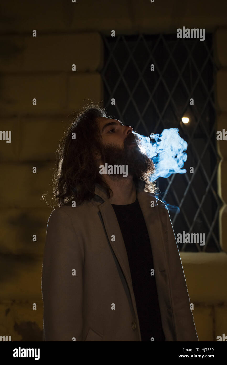 Stylish young man smoking outdoors at night Stock Photo - Alamy