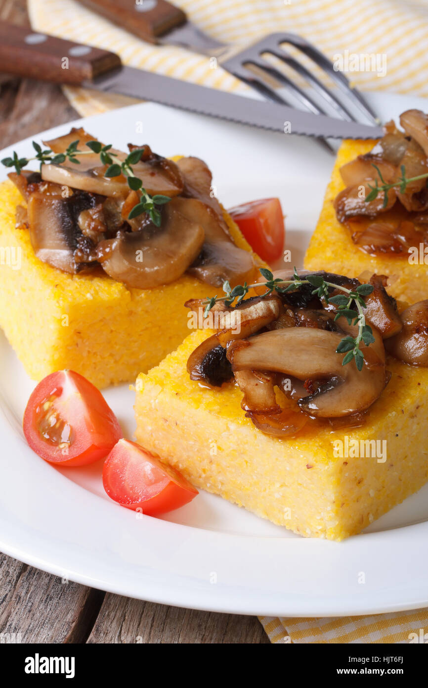 Polenta with mushrooms, tomatoes and thyme on the table. closeup ...
