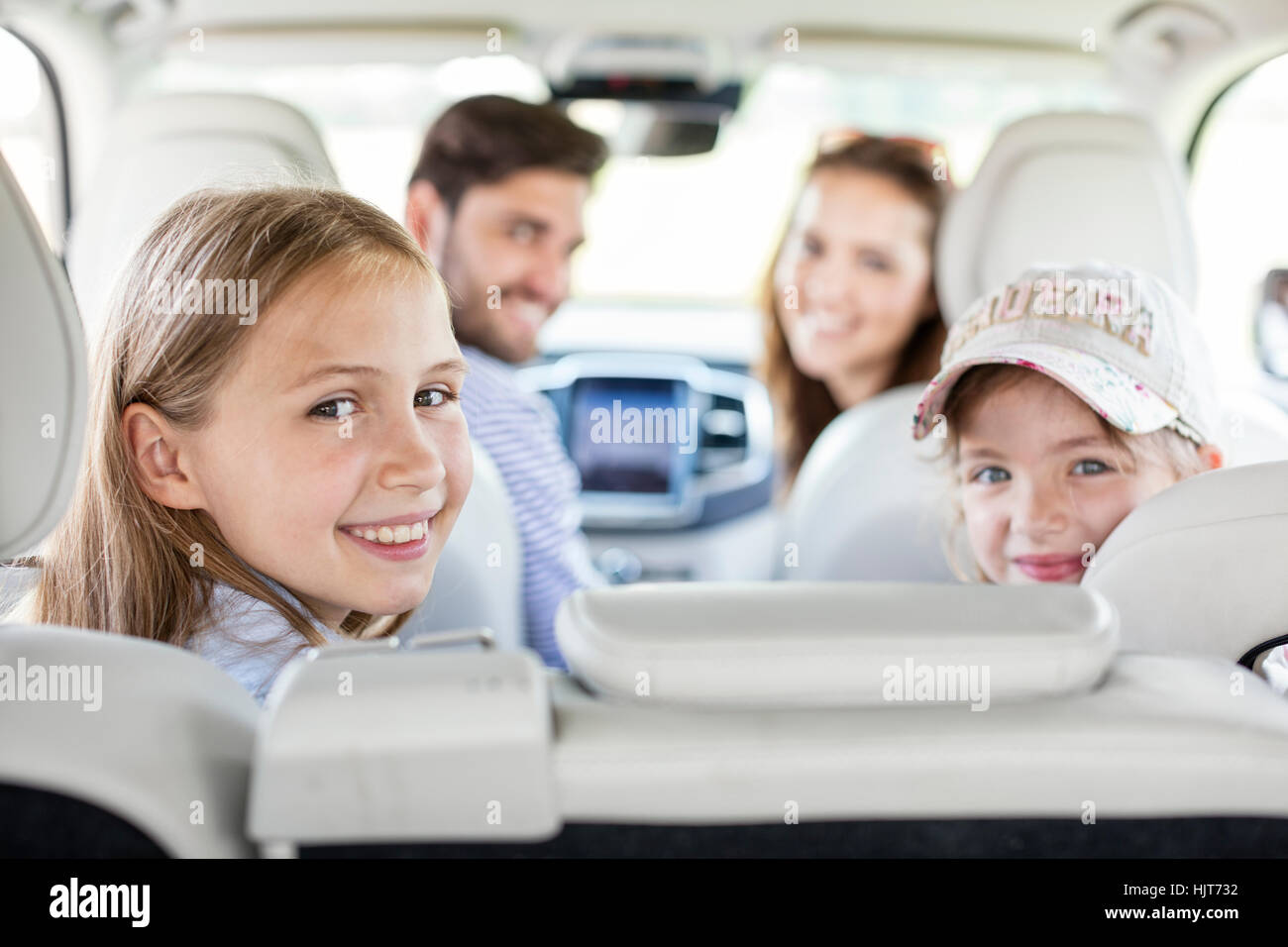 Happy family doing a road trip, looking over shoulder at camera Stock Photo - Alamy