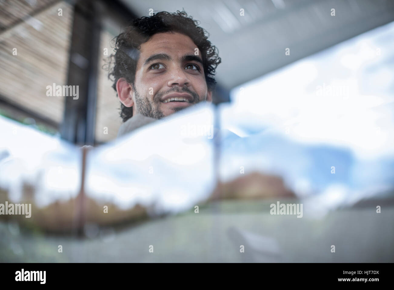 Smiling young man behind windowpane Stock Photo - Alamy