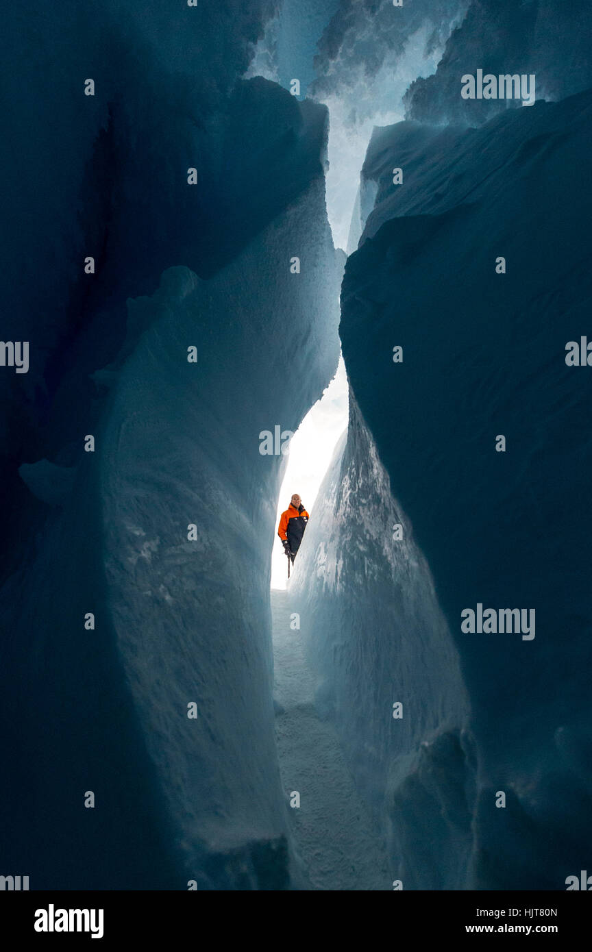 An ice guide examines the frozen ceiling and icy walls of an ice cave ...