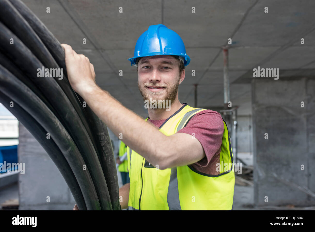 Construction worker on construction site, carrying cable Stock Photo ...