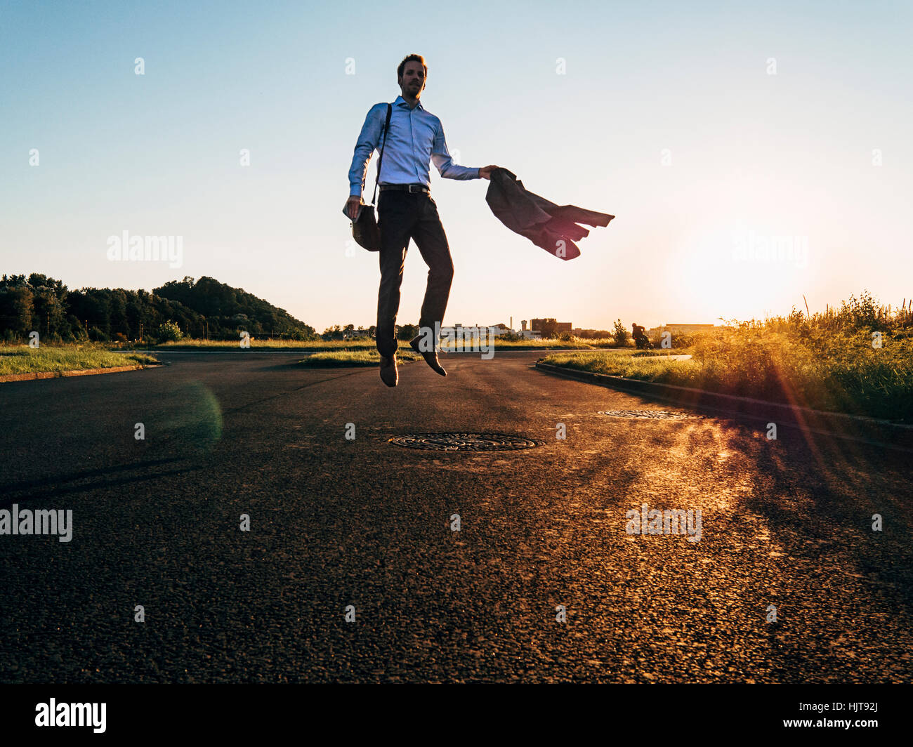 Businessman jumping on rural road Stock Photo - Alamy
