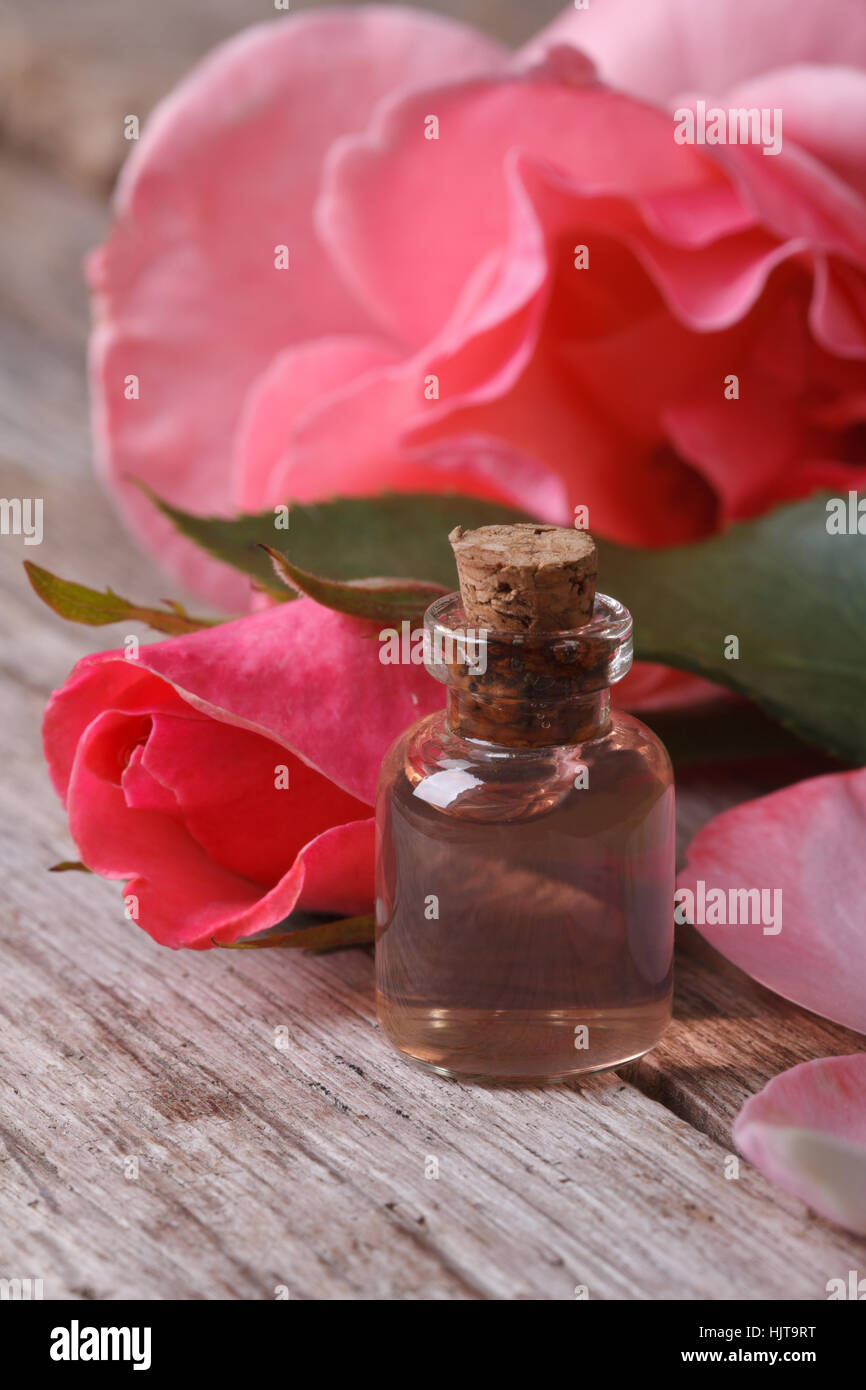 Rose water in a glass bottle on a background of pink roses close up ...