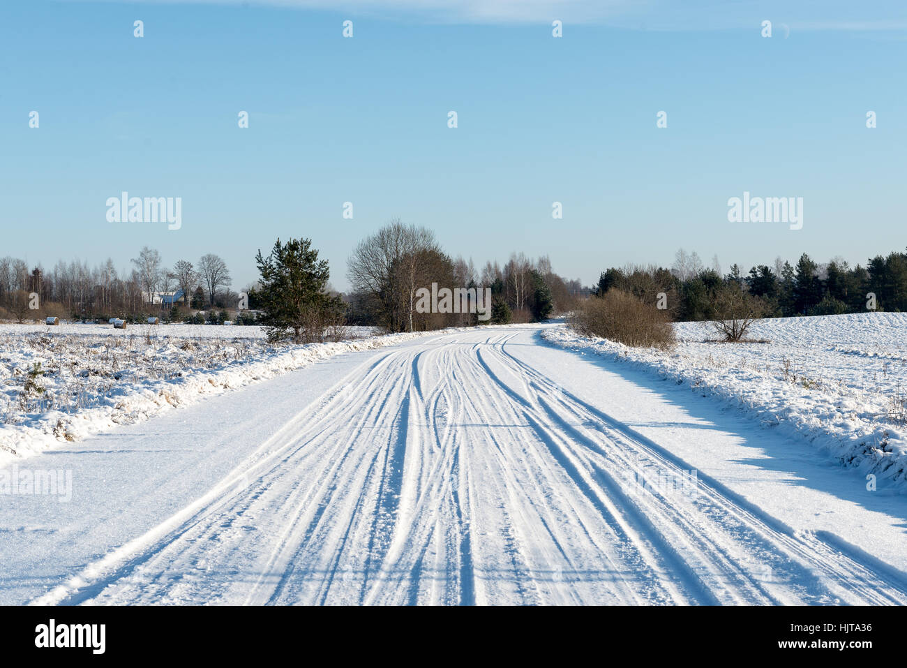 snowy winter road with tire markings and blue sky Stock Photo - Alamy