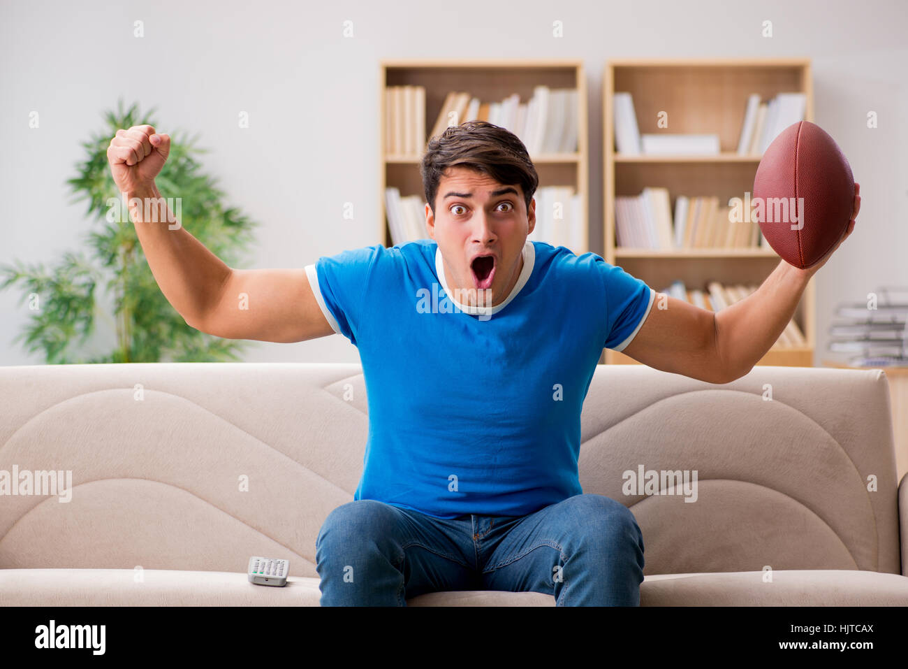 Man watching football at home sitting in couch Stock Photo - Alamy