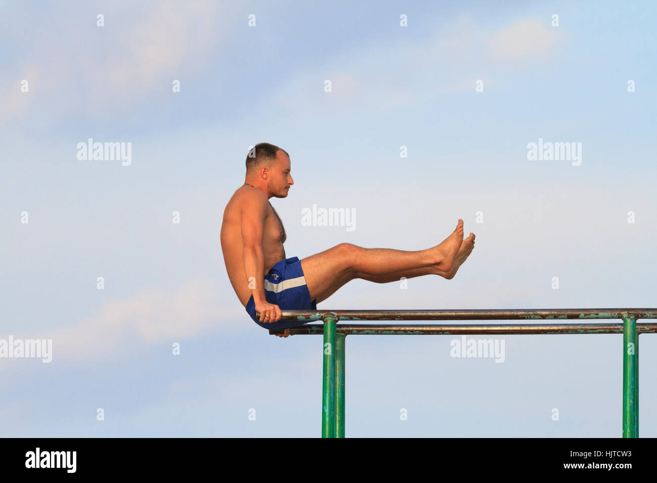 guy playing sports on parallel bars,against the sky, blue shorts Stock ...