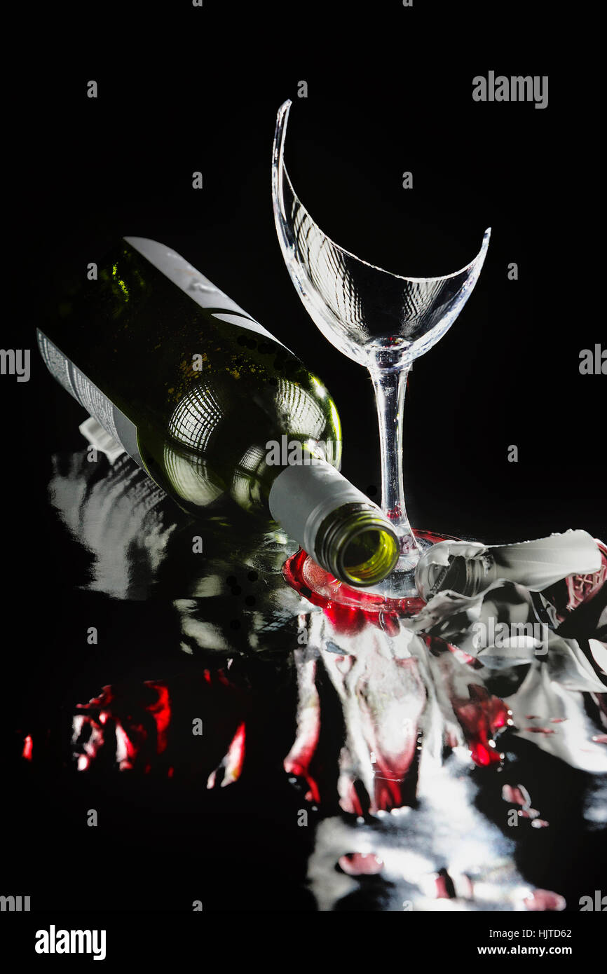 Broken wine glass with bottle and foil, on black background with cherry ...