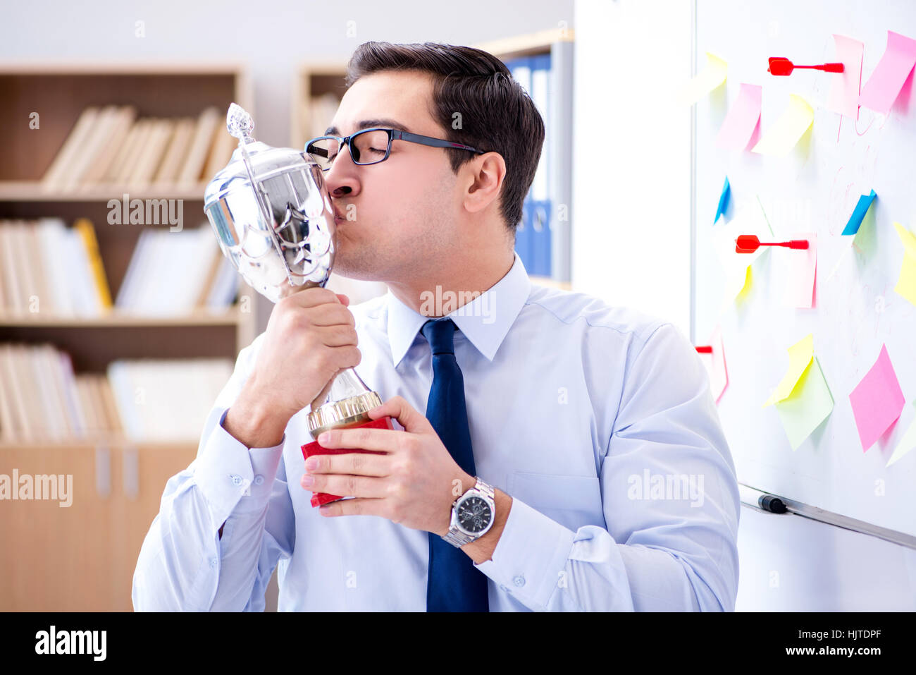 Young businessman receiving prize cup in office Stock Photo - Alamy