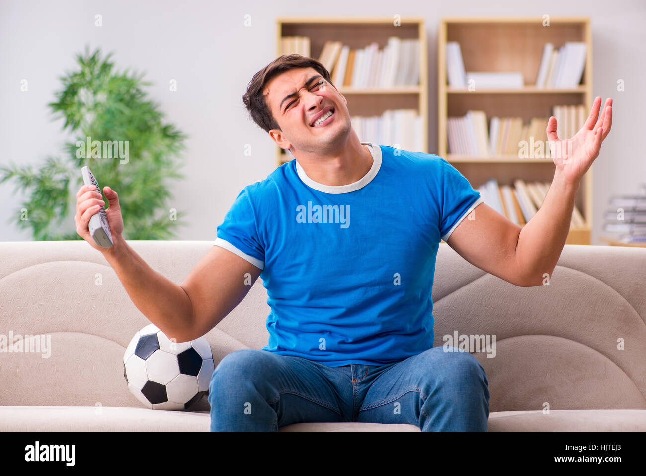 Man watching football at home sitting in couch Stock Photo - Alamy