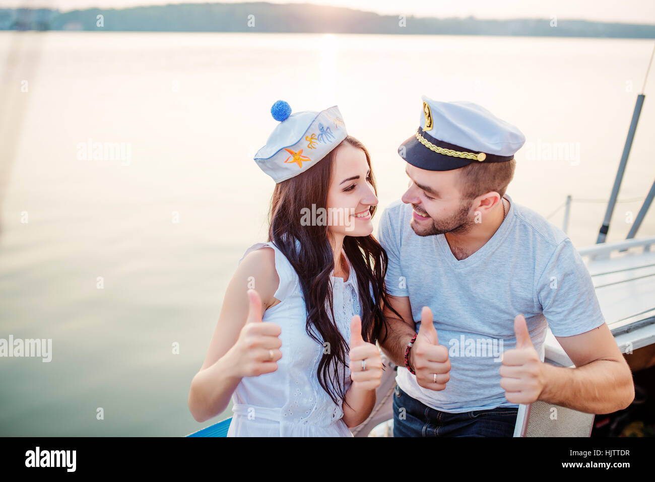 Young beautiful married couple in love at the yacht on vacation wearing ...