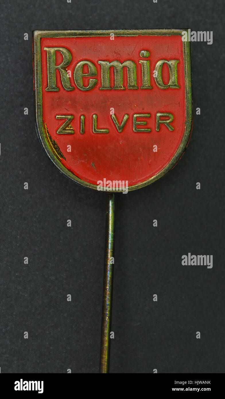 A vintage advertising pin for Remia, featuring their silver label ...